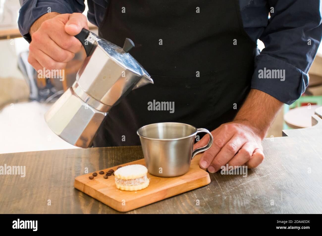 Male Barista preparing fresh espresso in coffee maker for customer in a ...