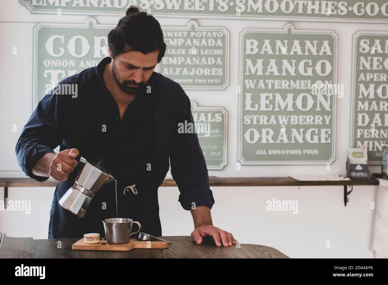 Male Barista preparing fresh espresso in coffee maker for customer in a ...