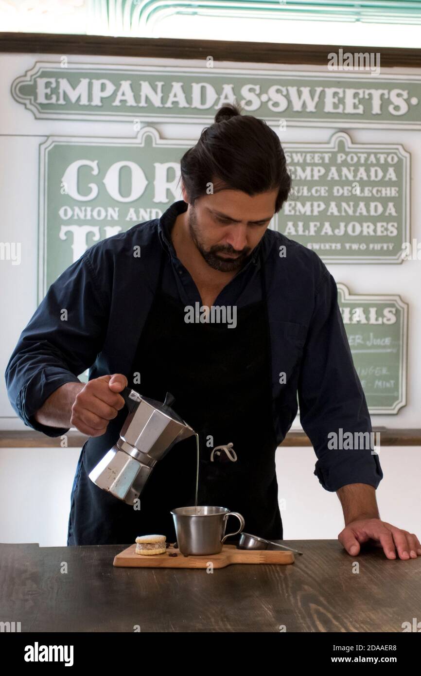 Male Barista preparing fresh espresso in coffee maker for customer in a ...