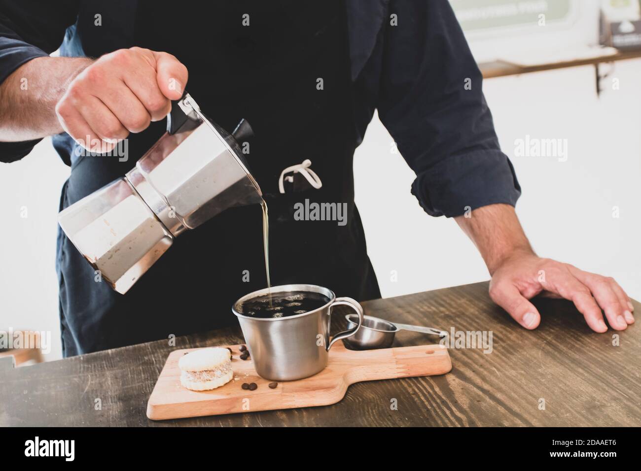 Male Barista preparing fresh espresso in coffee maker for customer in a ...