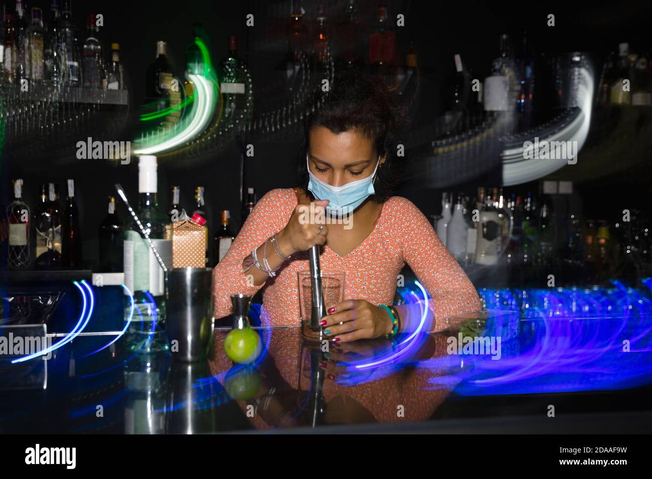 Latin american waitress wearing a face mask working at a nightclub bar ...
