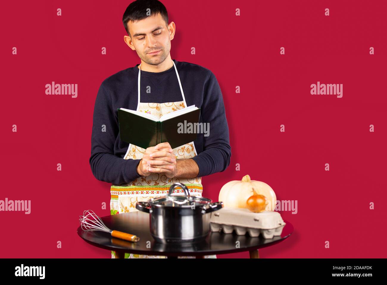 Young man in the kitchen, reading a cookbook of recipes. Gender ...