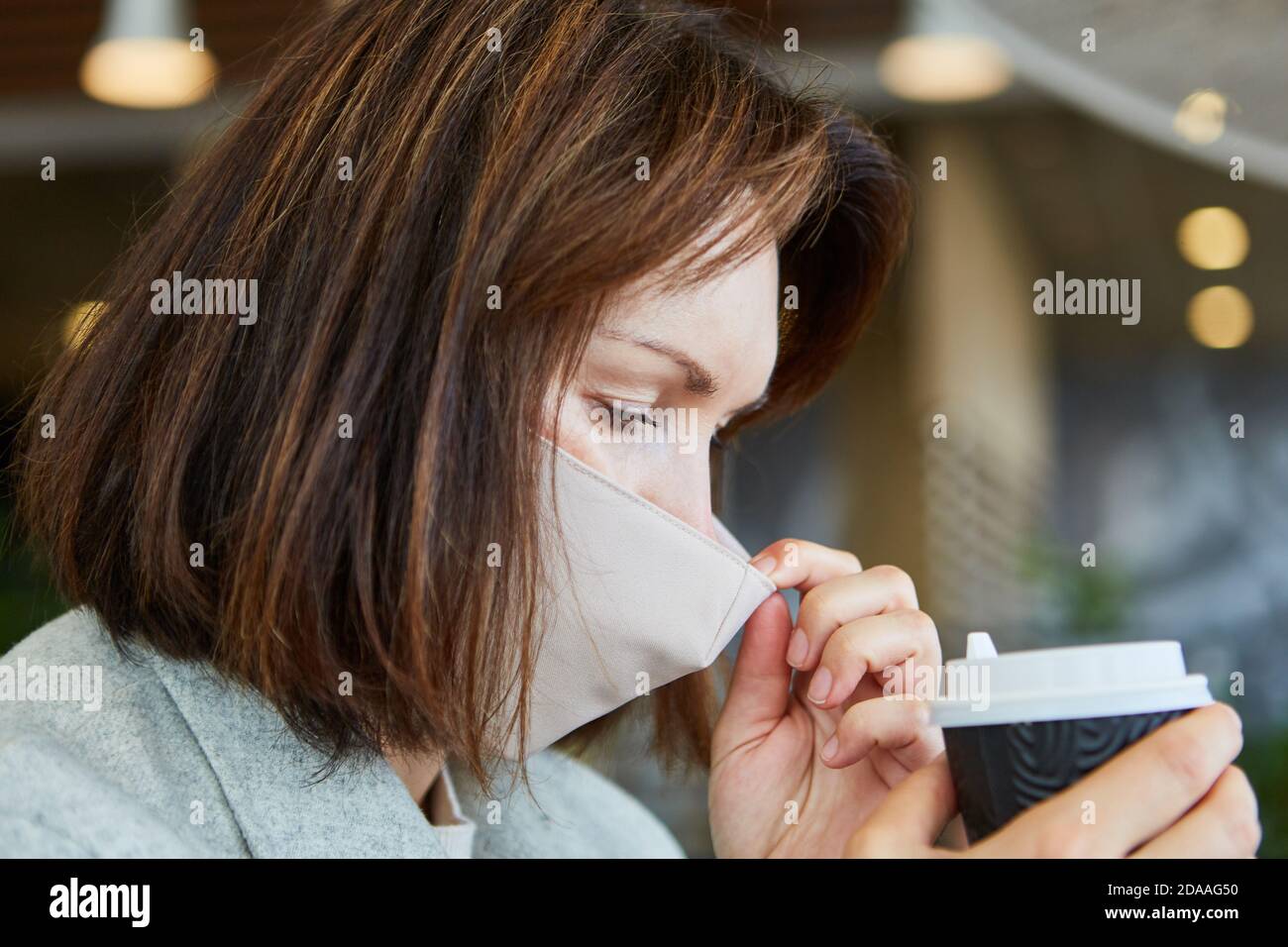 Woman with a mask because of Covid-19 pandemic with a mug of coffee in ...