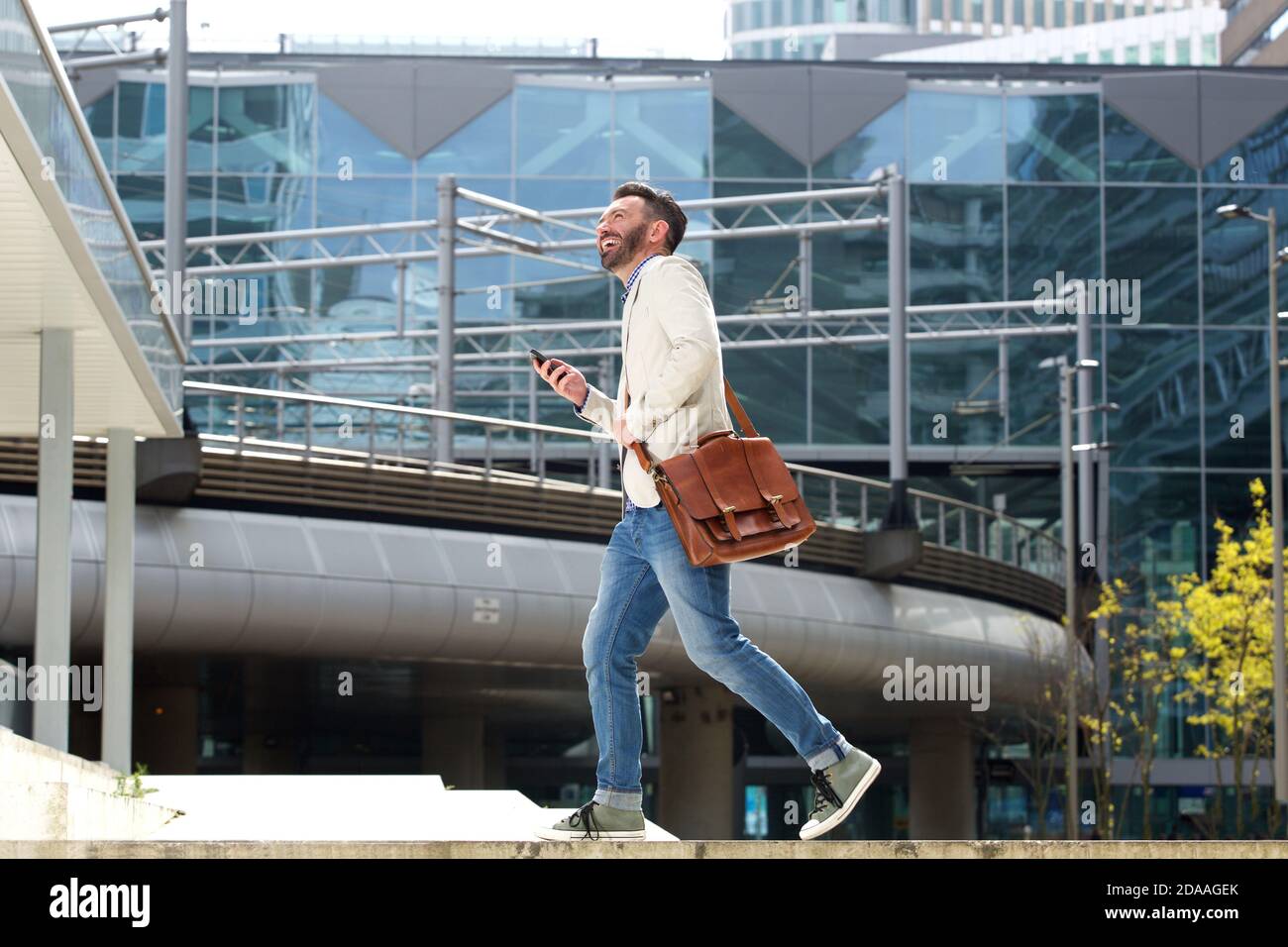 Full length side portrait of cheerful middle aged man walking outdoors ...