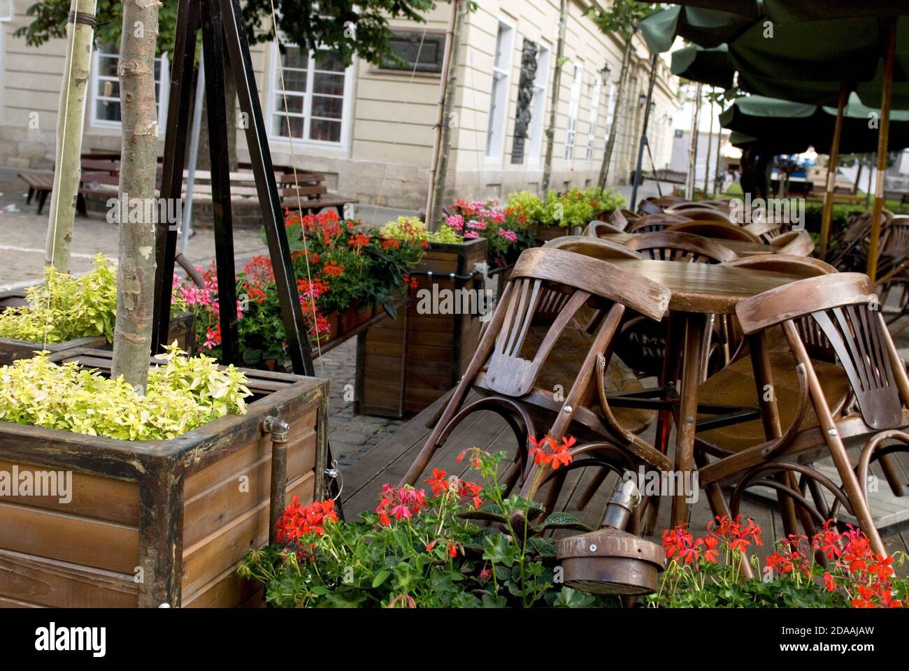 Closed cafe restaurant with wood chairs, stacked upon tables outdoor in ...