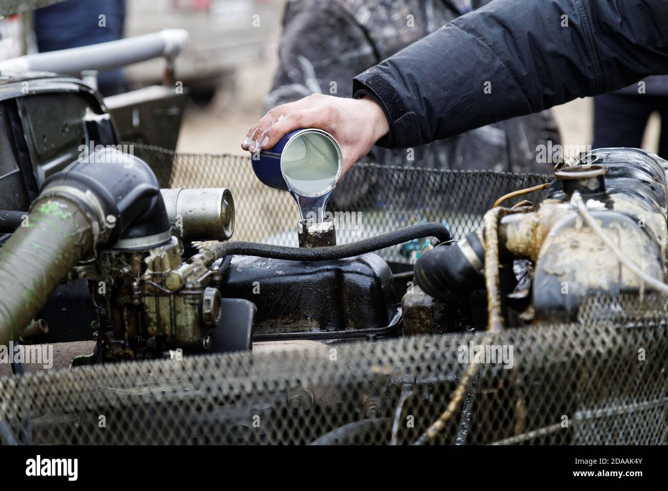 The auto mechanic pours the engine oil additive in motor of old ...