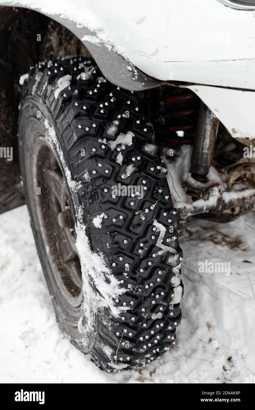 Closeup winter wheel with iron spikes for mud and snow terrain. Shallow ...