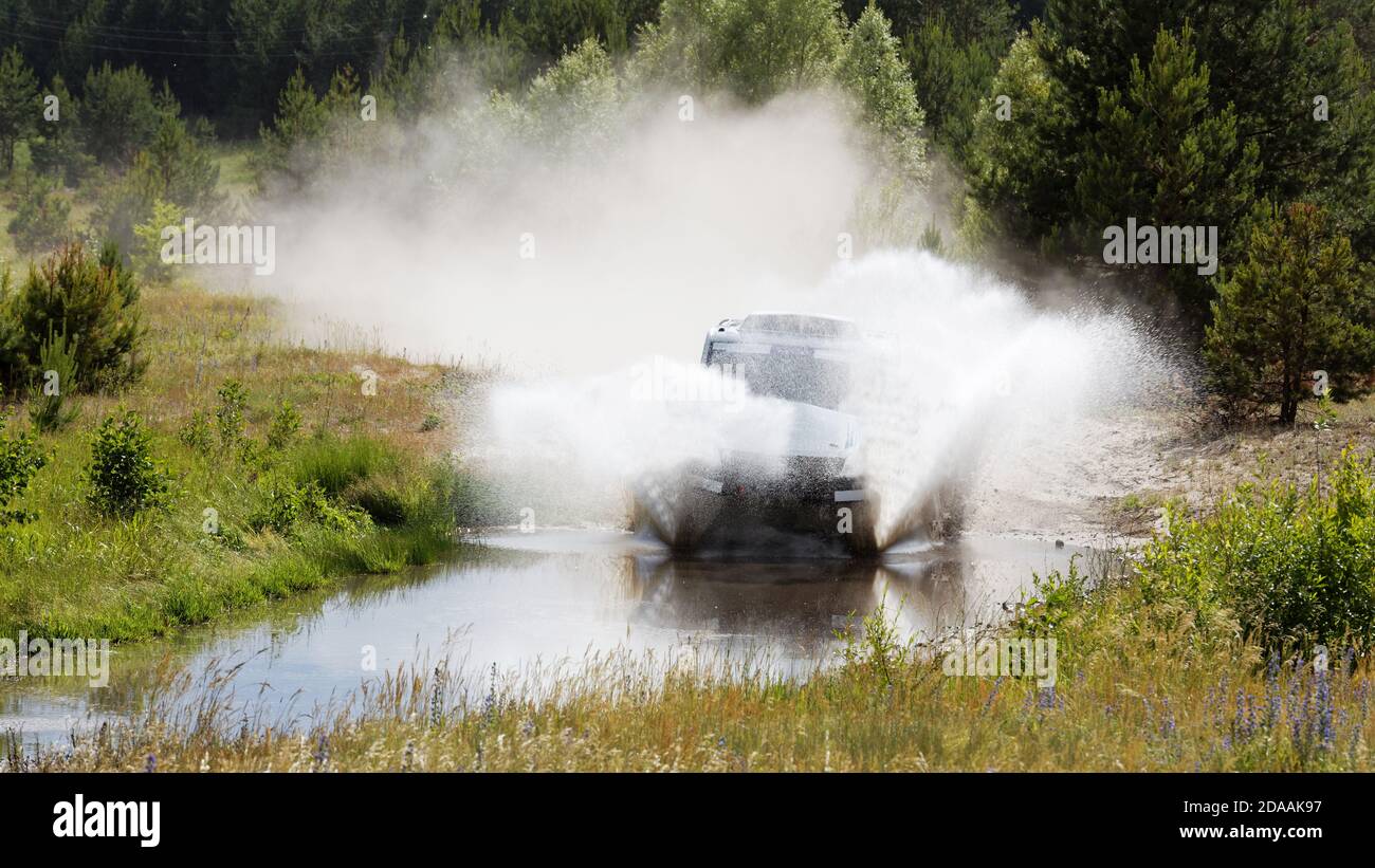 A 4wd car overcomes a water obstacle at high speed surrounded by spray ...