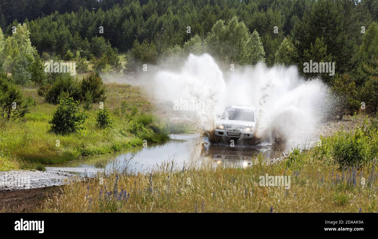 A 4wd car overcomes a water obstacle at high speed surrounded by spray ...