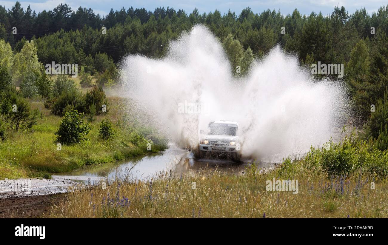 A 4wd car overcomes a water obstacle at high speed surrounded by spray ...