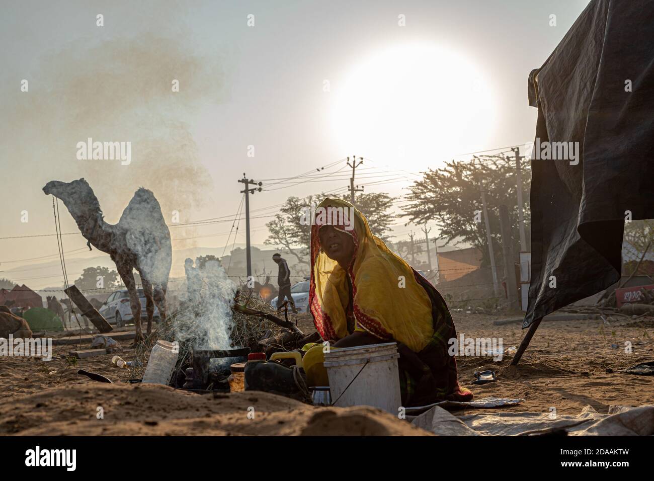 an indian woman making food,smoke is coming out from handmade clay ...