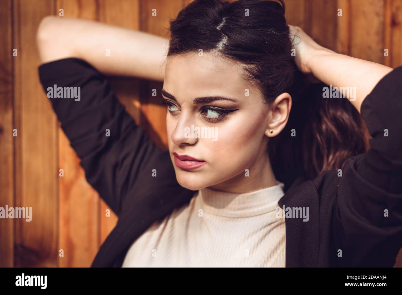 Portrait of a beautiful brunette girl with hazel eyes holding her hair ...