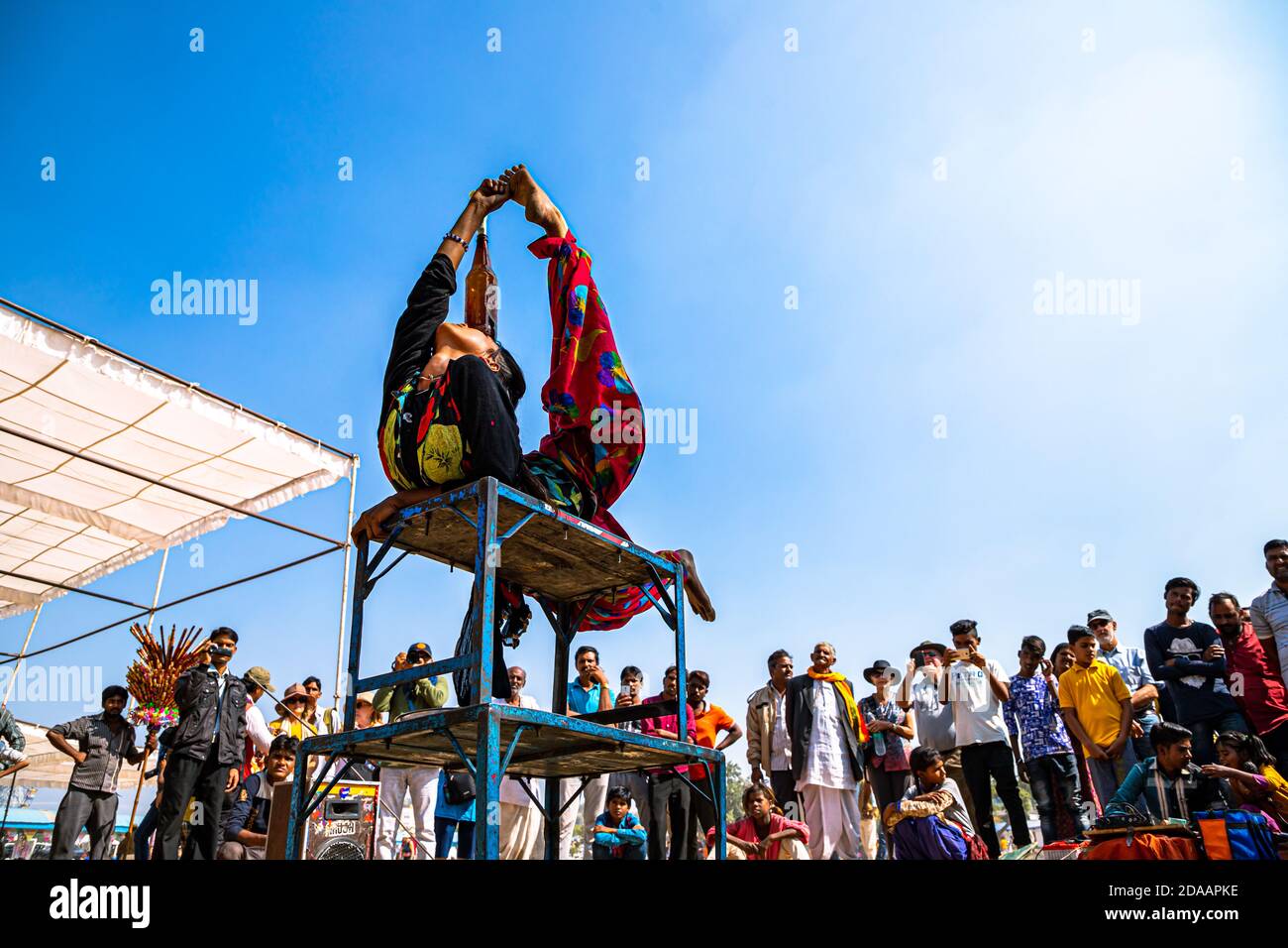 a girl perform street acrobatics by balancing bottle on head at pushkar ...