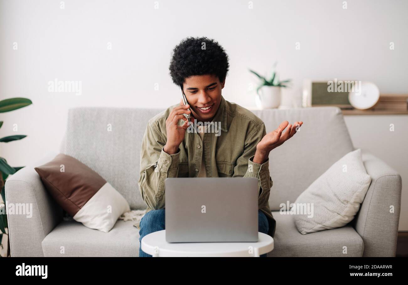 Distance learning concept. Happy black teenager talking on mobile phone ...