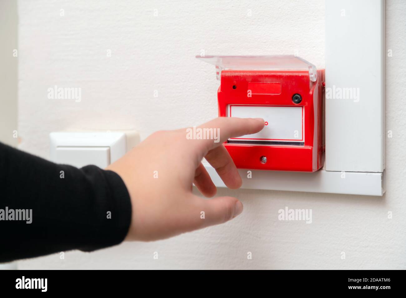 Hand pressing fire alarm button at school or business office. Close up ...