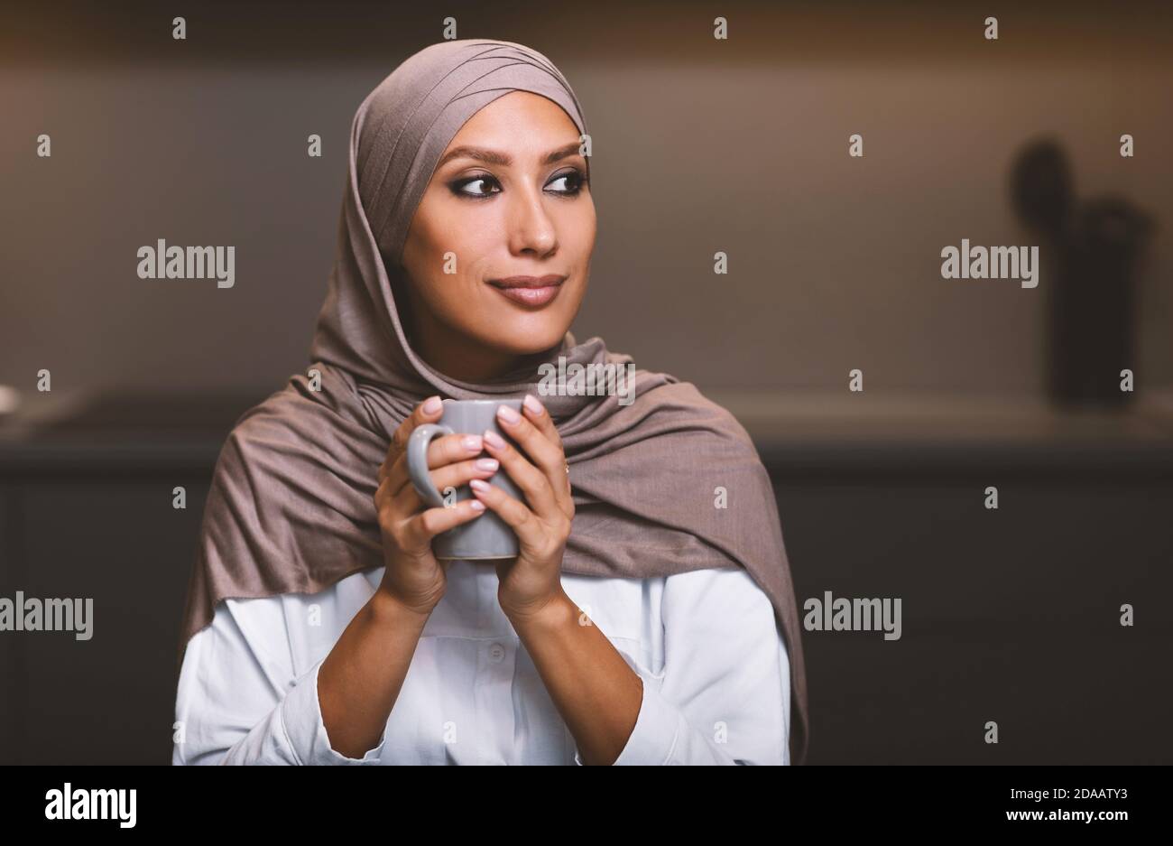 Muslim Woman Drinking Coffee Sitting And Relaxing In Kitchen Stock ...