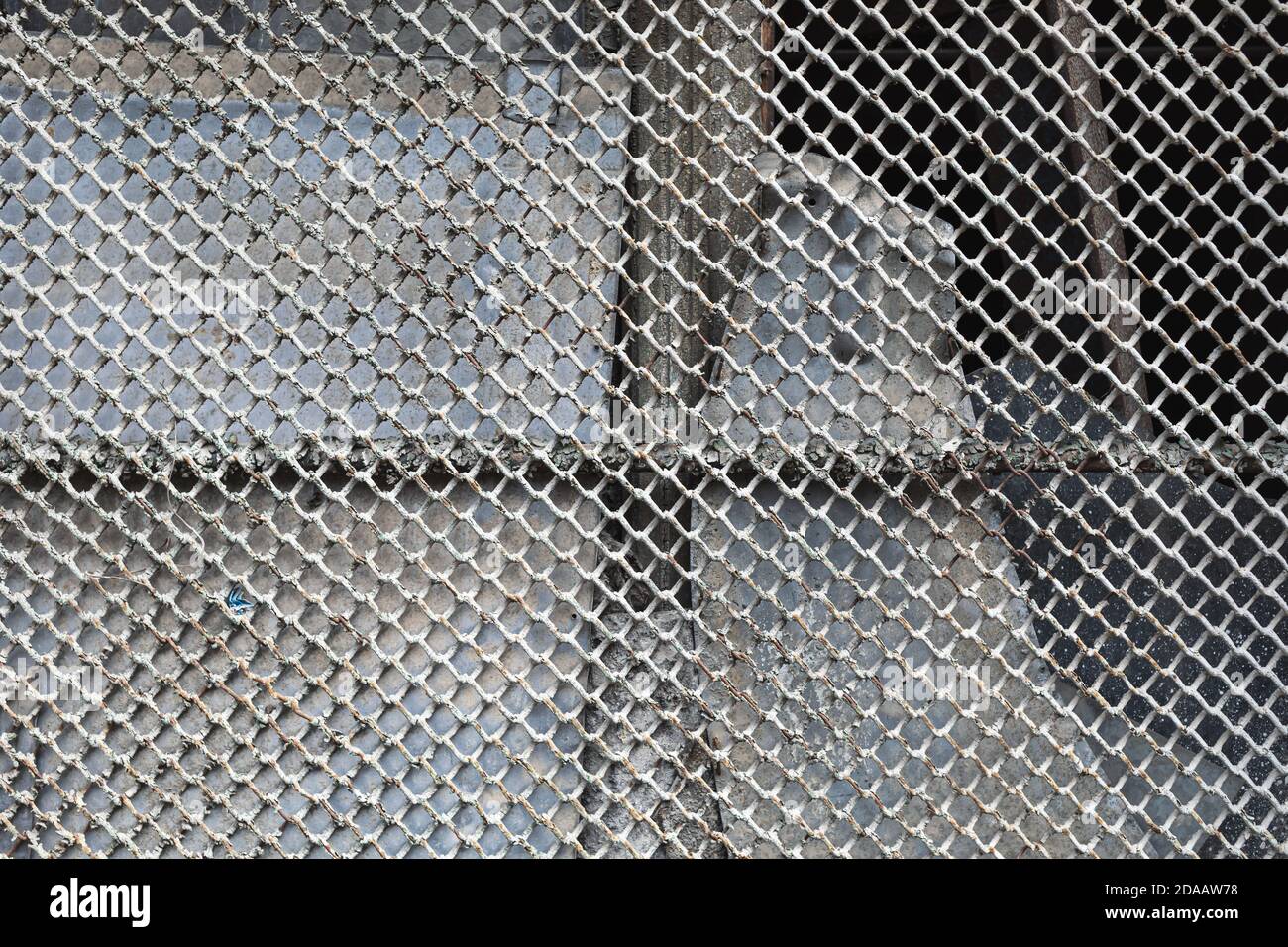 Old metal mesh on a broken window. Broken glass behind a rusty metal ...