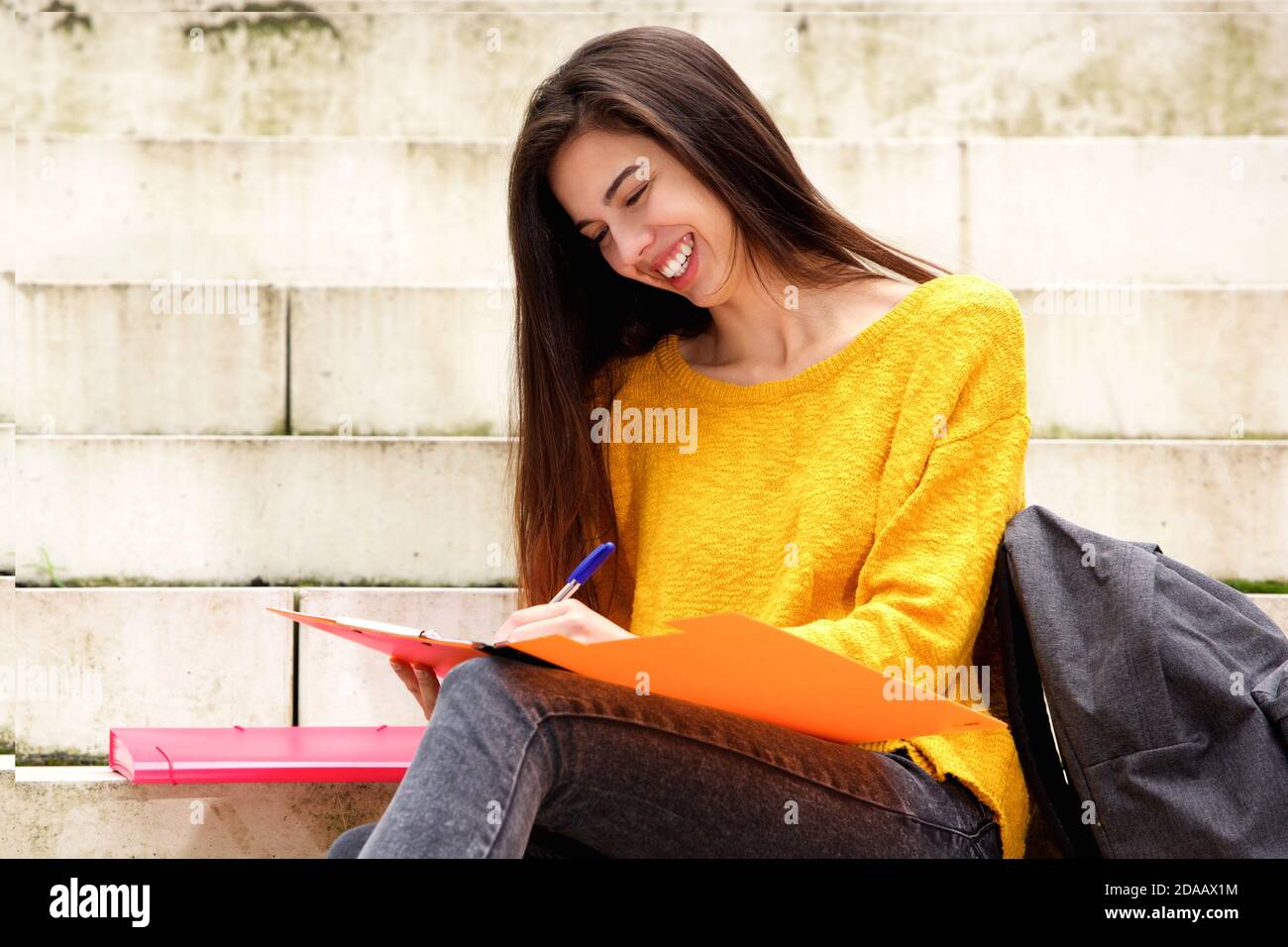 Portrait of smiling student taking notes on staircase Stock Photo - Alamy