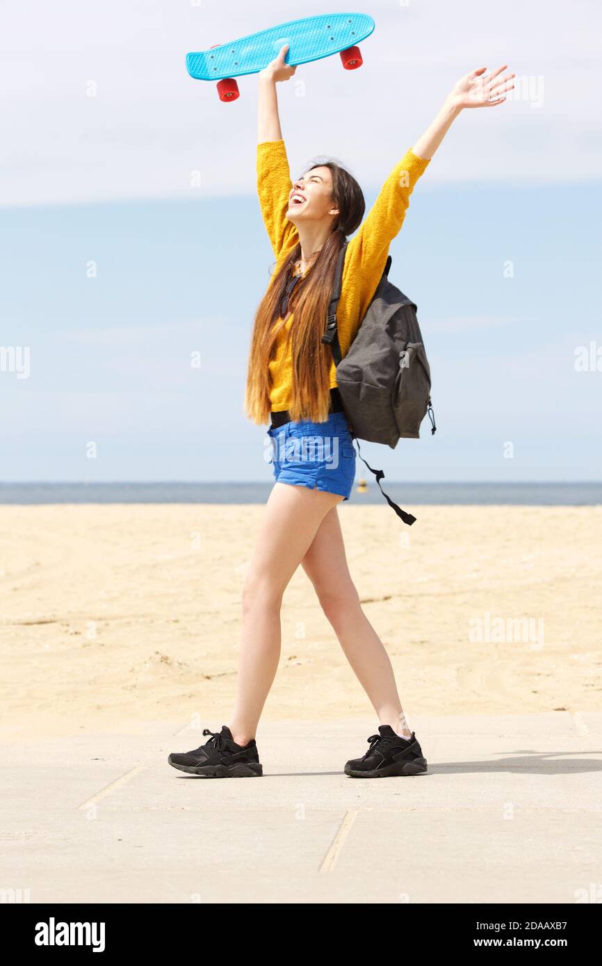 Full body portrait of carefree young woman with skateboard Stock Photo ...