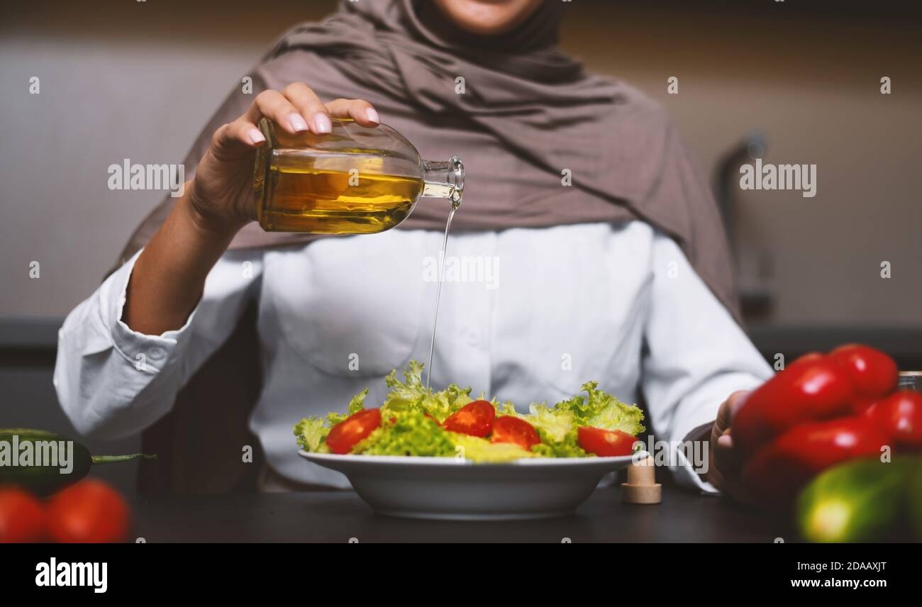 Muslim Lady Cooking Drizzling Olive Oil On Salad In Kitchen Stock Photo ...