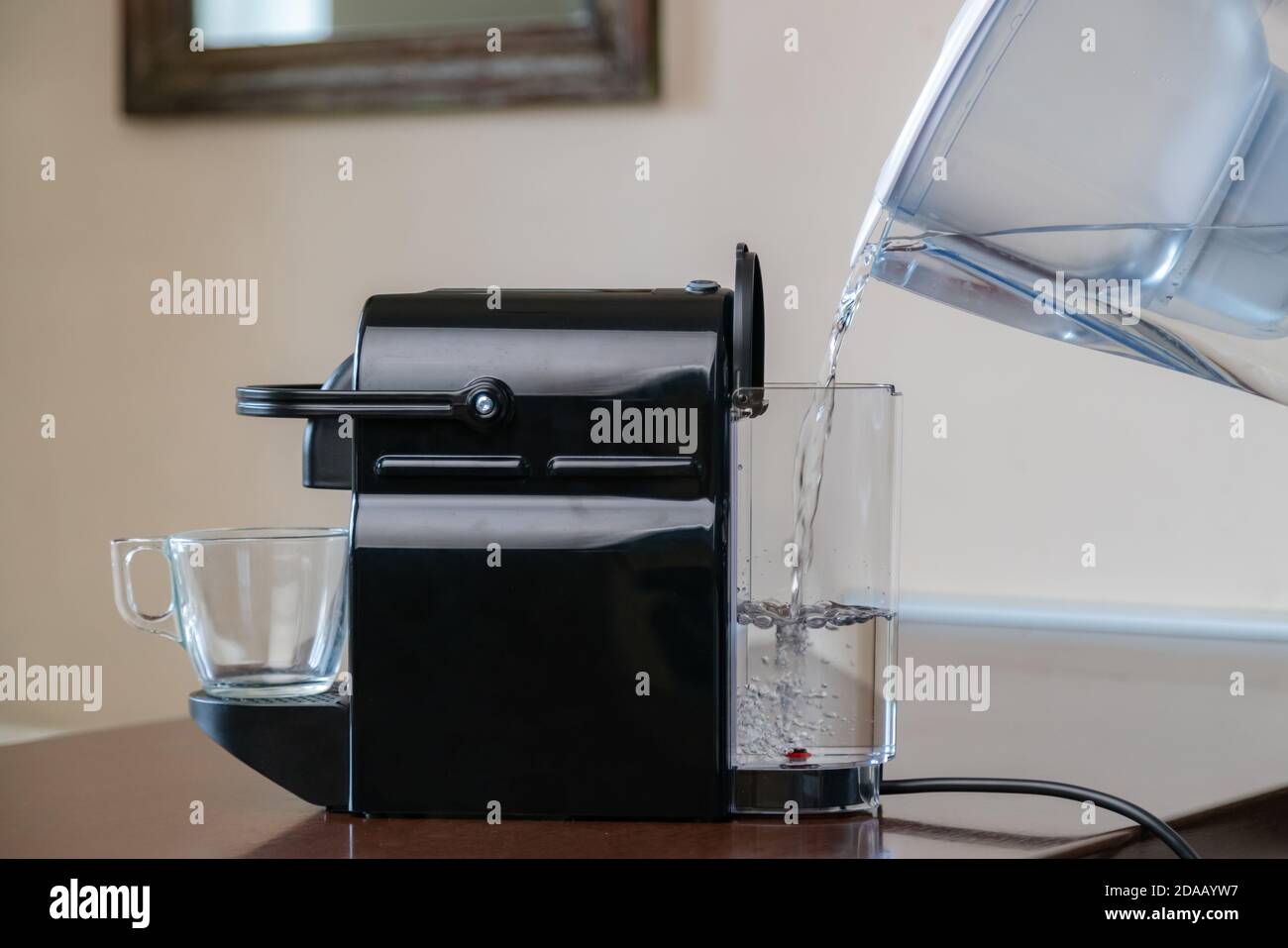 Close up of hand pouring pure filtered water into capsule coffee ...