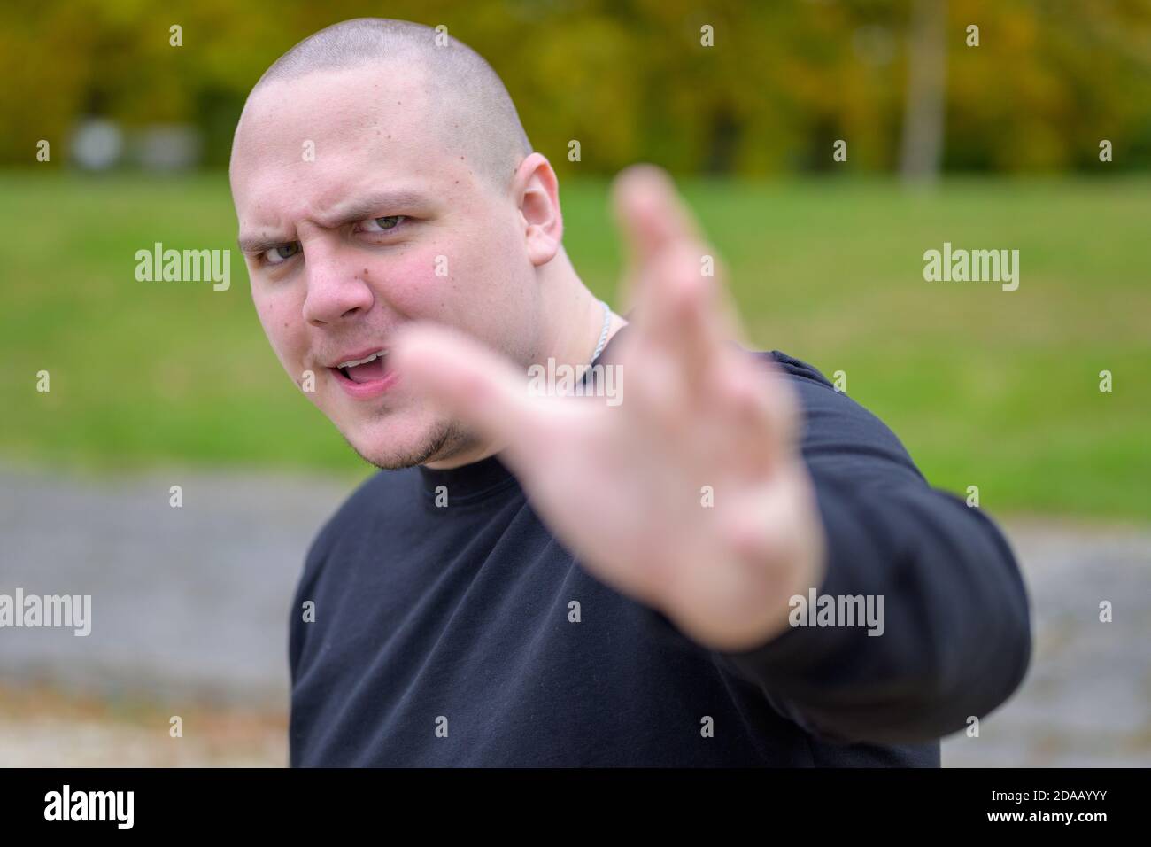Young man with a vindictive vengeful expression gesturing with his hand ...