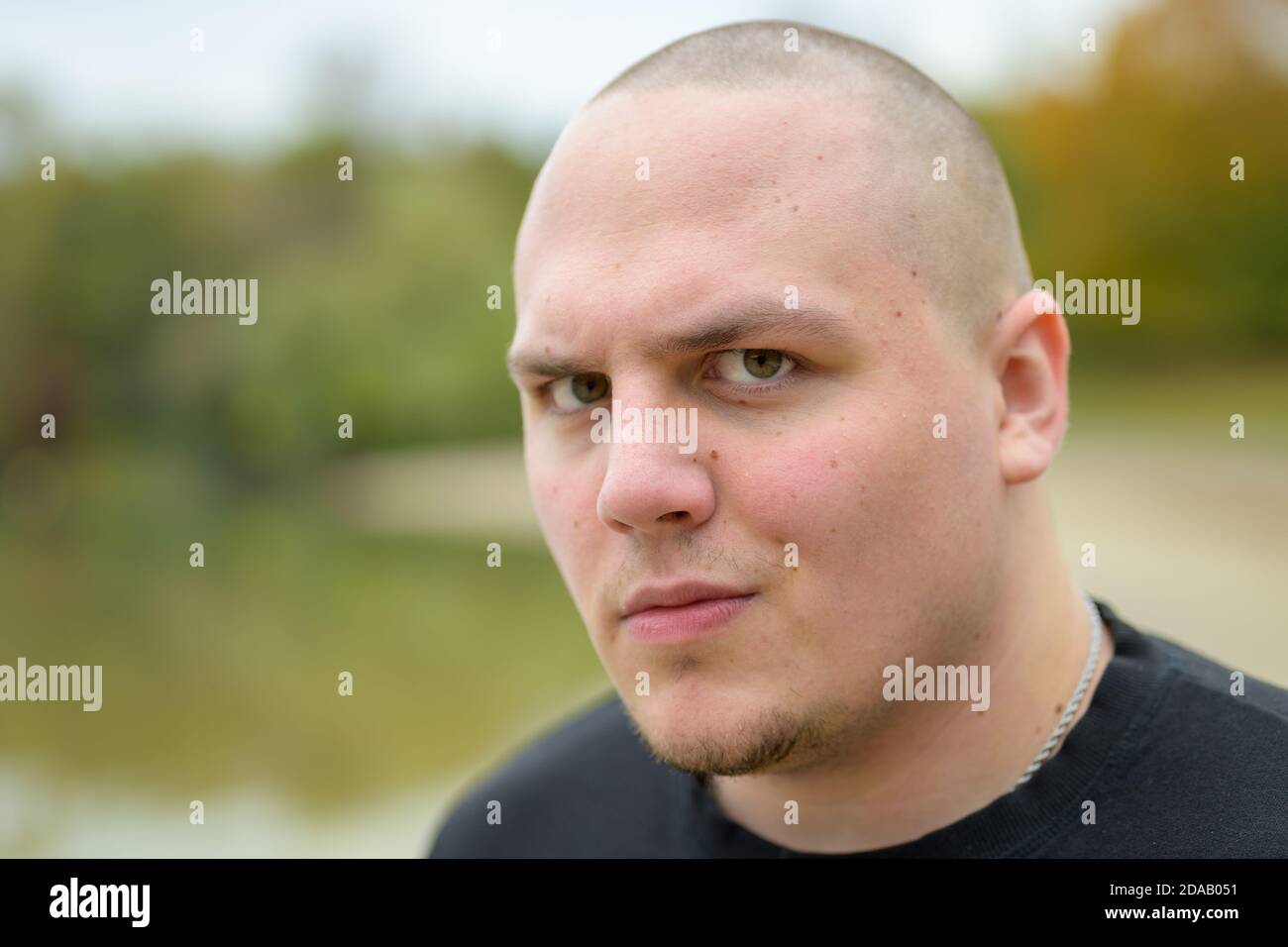 Sceptical young man looking sideways at the camera with a puzzled frown ...