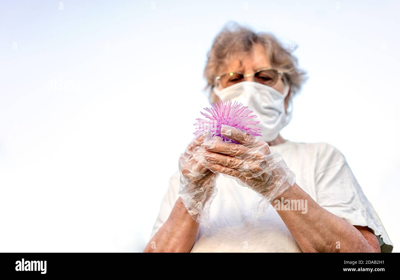Old woman in mask and gloves holds ball looks like coronavirus in her ...