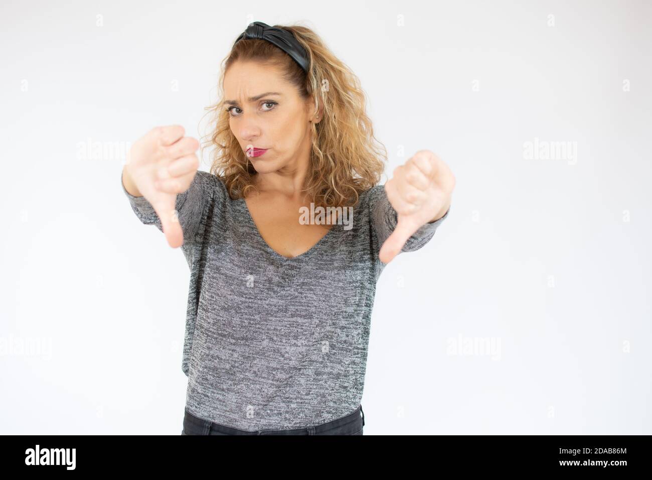 Young woman isolated on white background showing thumb down with two ...