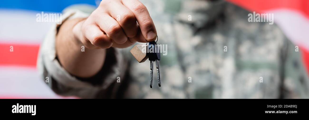 partial view of patriotic military man holding keys near american flag ...