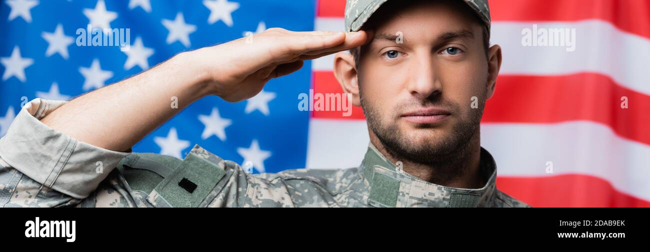 patriotic military man in uniform and cap giving salute near american ...