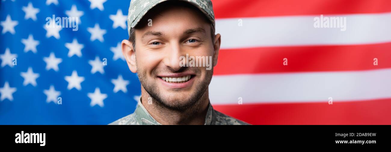 happy military man in uniform and cap smiling near american flag on ...