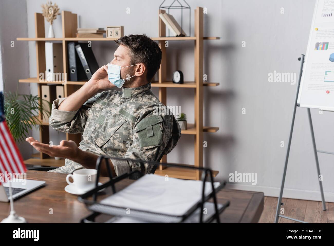 military man in uniform and medical mask talking on smartphone near ...