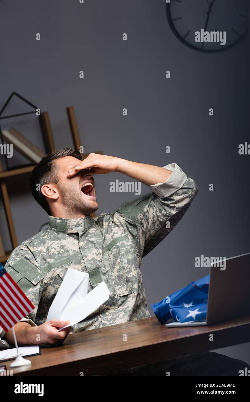 angry military man in uniform covering eyes and holding letter while ...