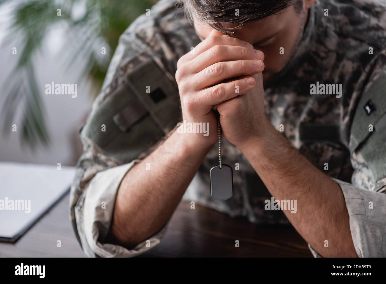 sad soldier in camouflage uniform holding military tag in clenched ...