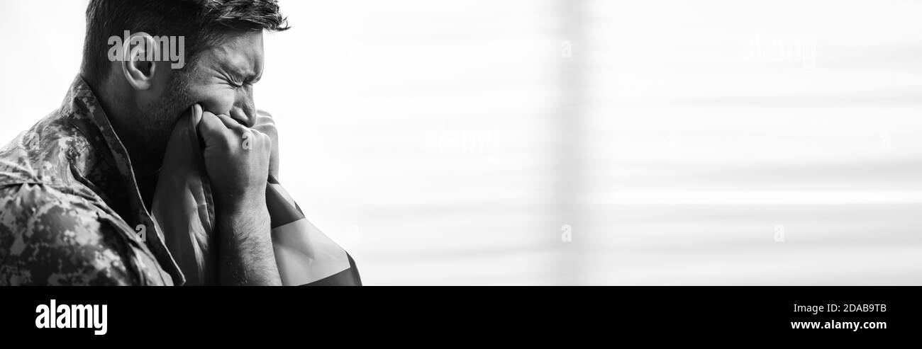 side view of military man in uniform crying while holding flag of ...