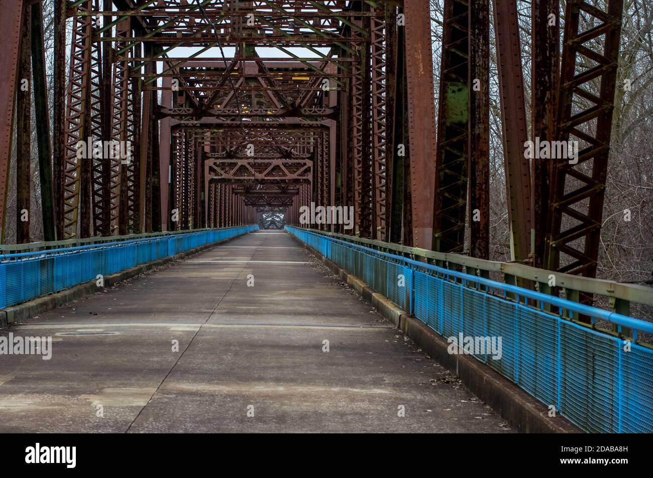 Old rusty steel truss bridge going into background with concrete deck ...