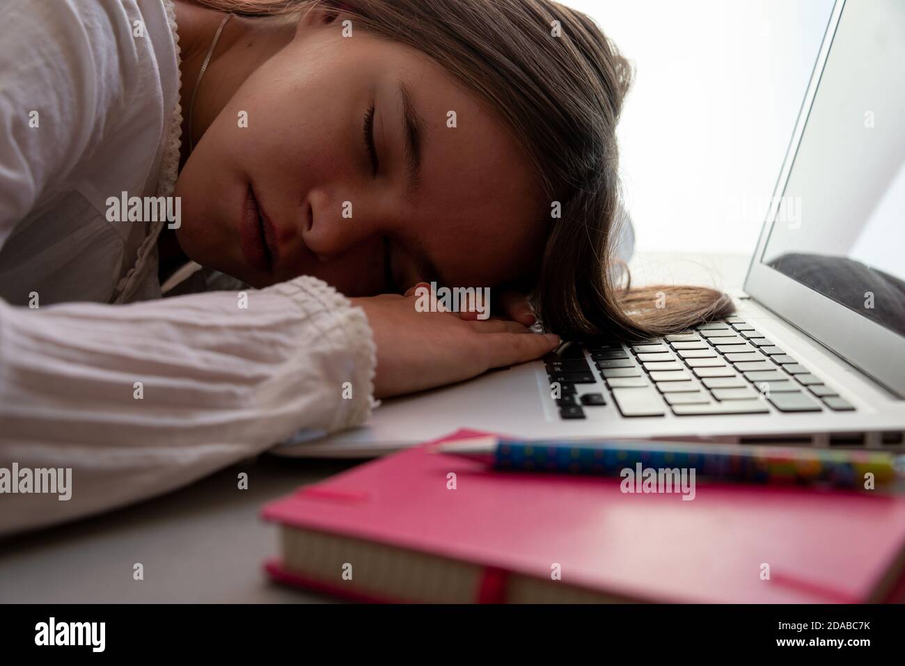 young woman sleeping with head on computer keyboard , student or ...