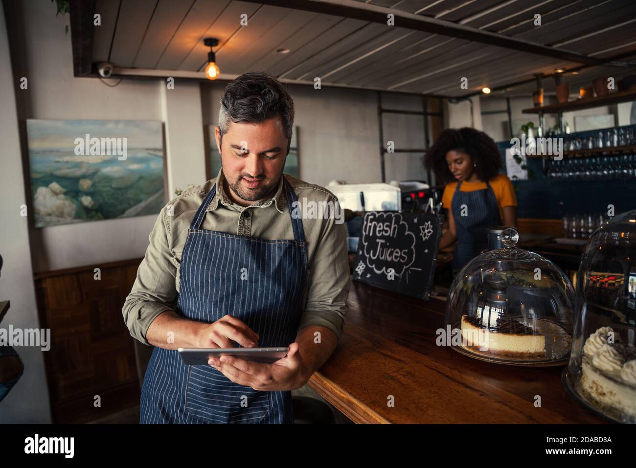 Male waiter scrolling on digital tablet searching for menu while ...