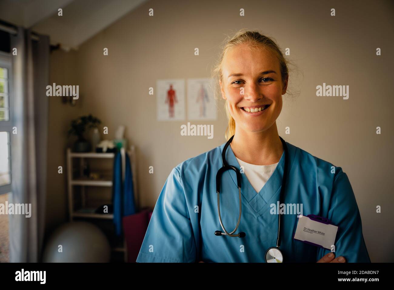 Caucasian nurse standing with cross-arms wearing overalls in neat ...