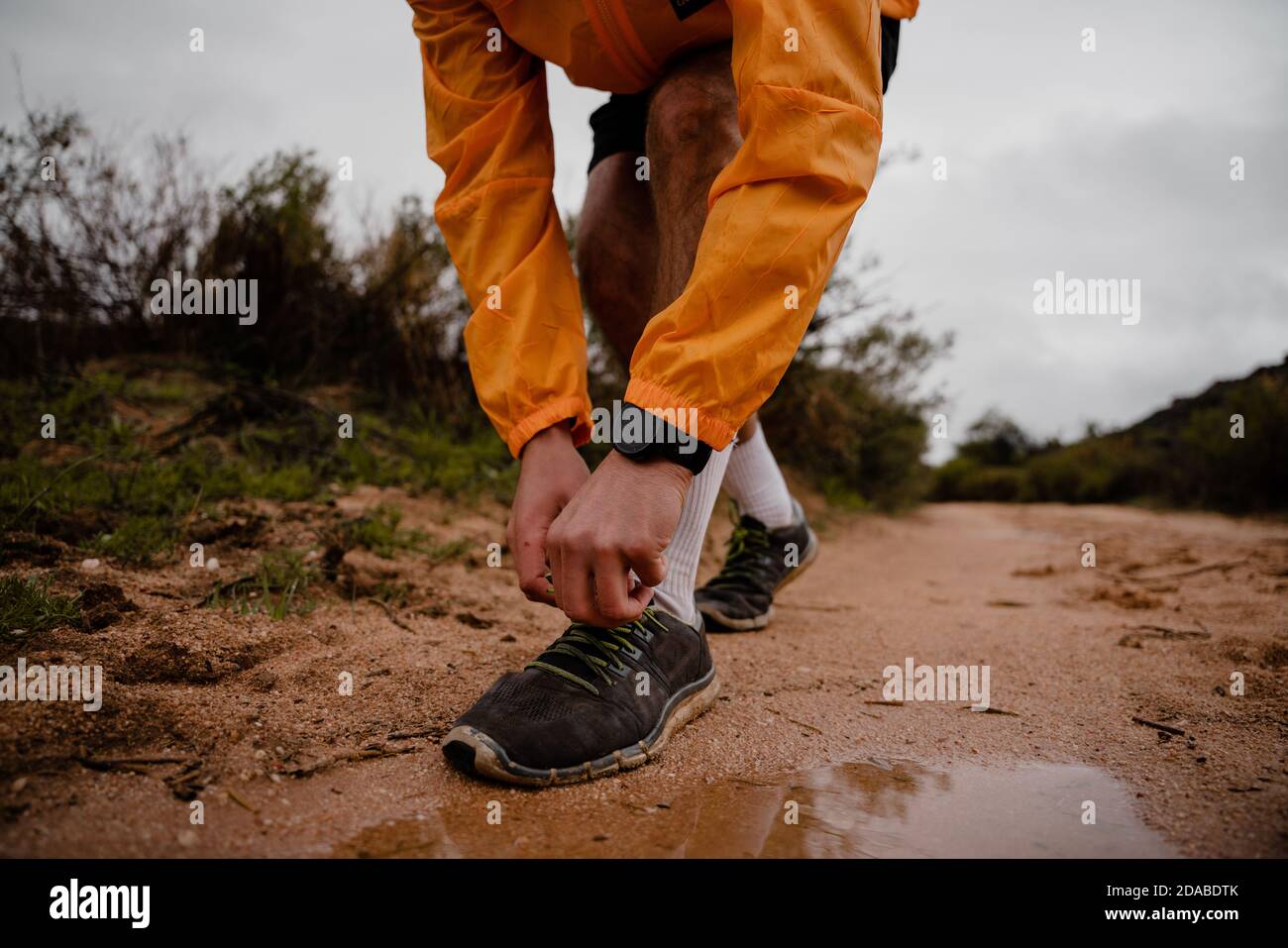 Young fit male athlete bending over tying shoe laces of running shoes ...