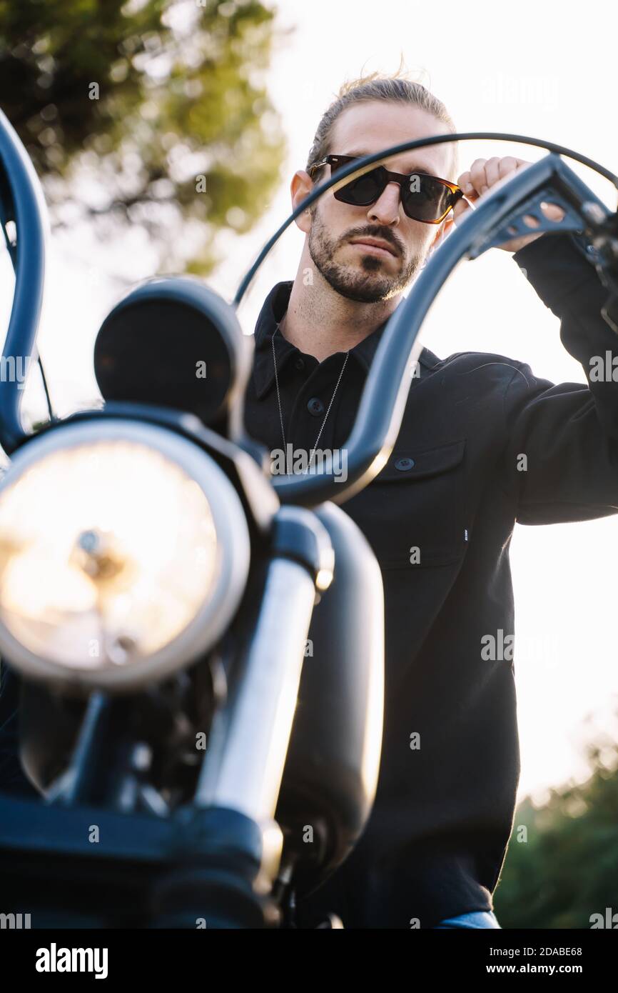 Vertical photo of a young man sitting on a motorcycle while taking off ...
