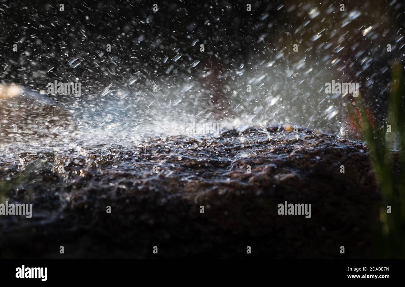 Wet stone in the rain. Rain water drop falling to the stone. Water is ...