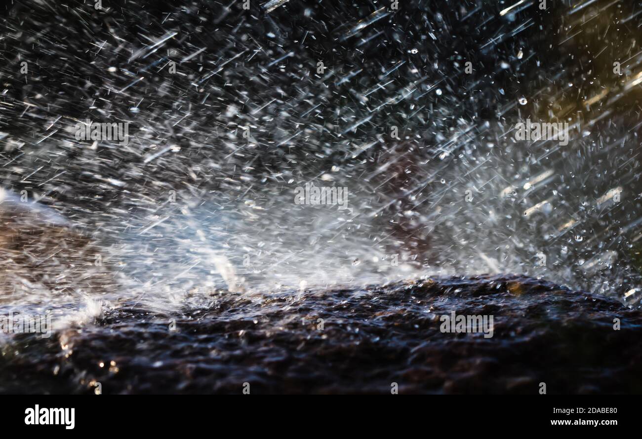 Wet stone in the rain. Rain water drop falling to the stone. Water is ...