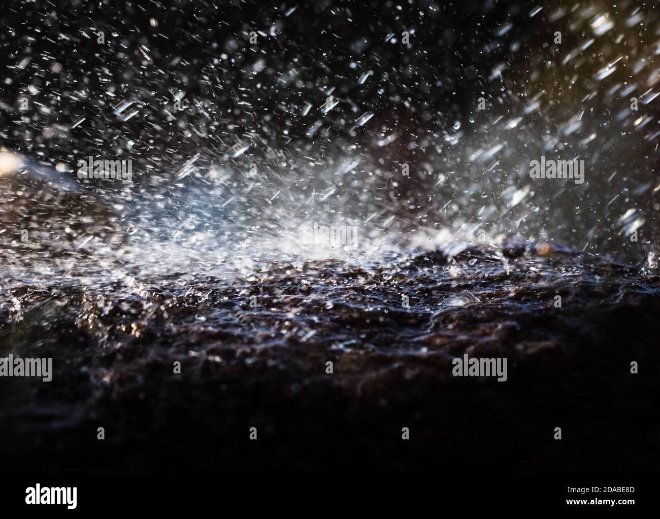 Wet stone in the rain. Rain water drop falling to the stone. Water is ...