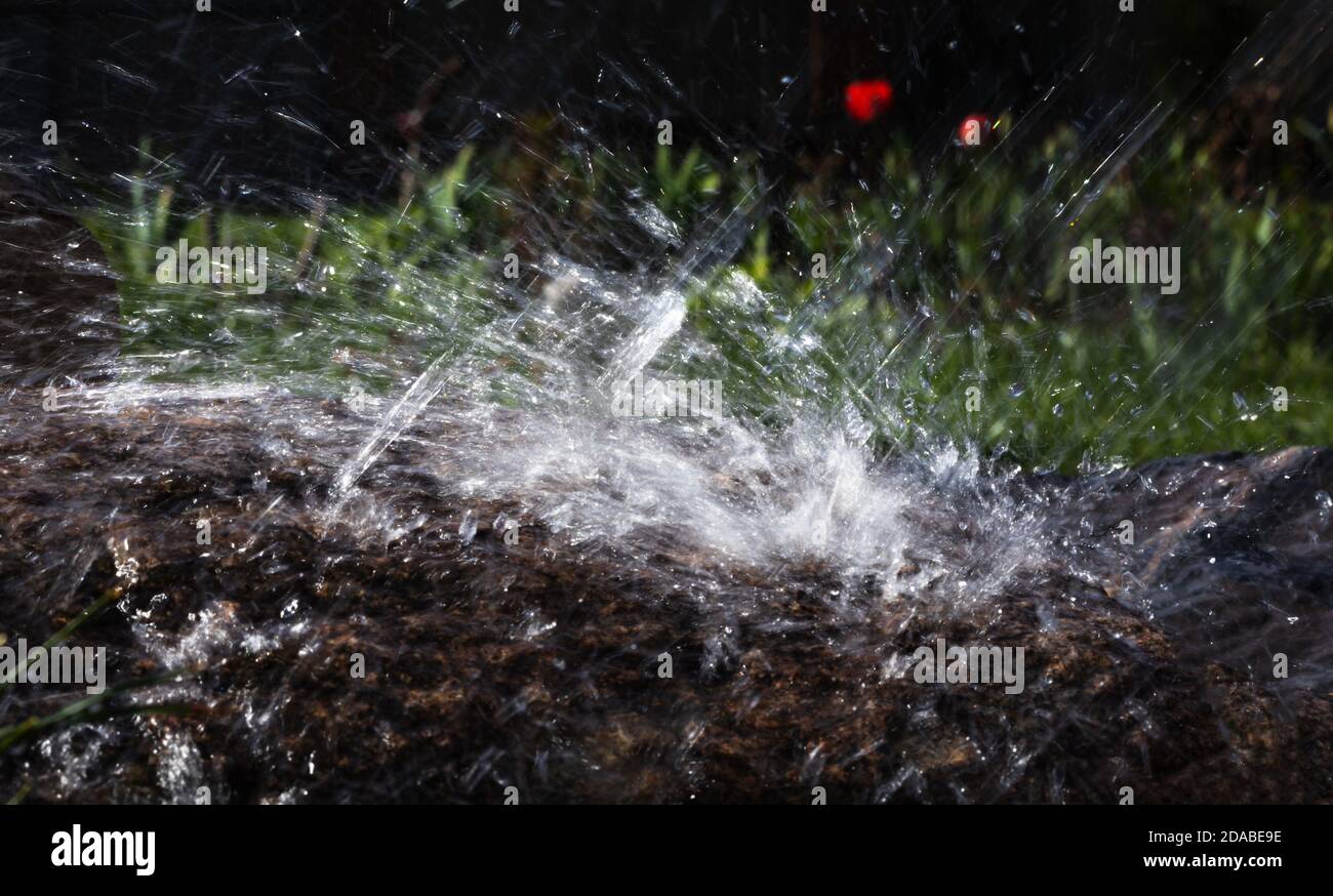 Wet stone in the rain. Rain water drop falling to the stone. Water is ...
