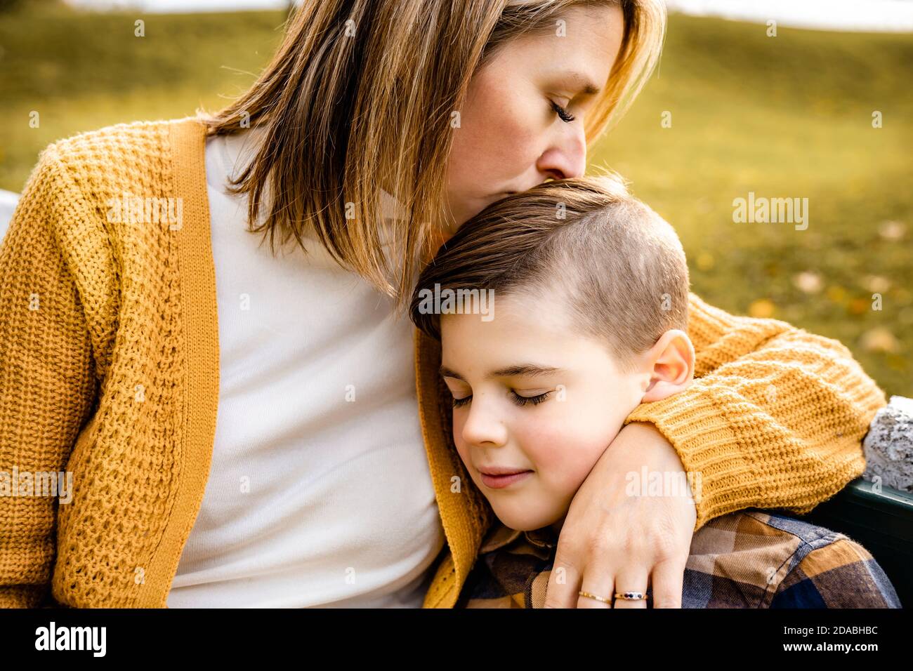 mother consoling child boy in the autumn leaf fall sit on bench Stock ...
