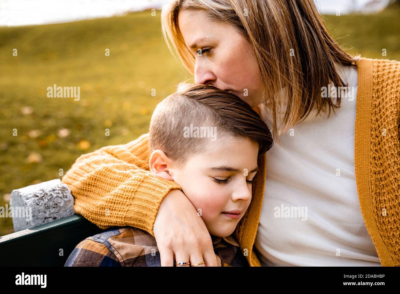 mother consoling child boy in the autumn leaf fall sit on bench Stock ...