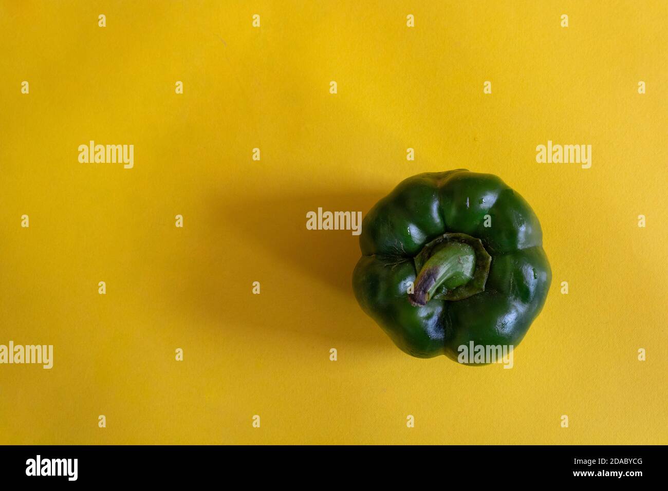 Top view of a green bell pepper with yellow background Stock Photo - Alamy