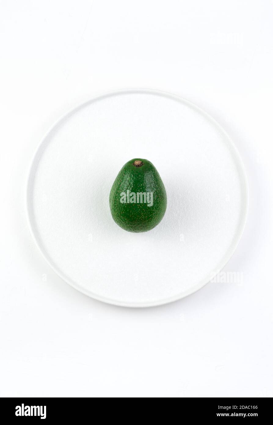 One uncut avocado on a light background Stock Photo - Alamy